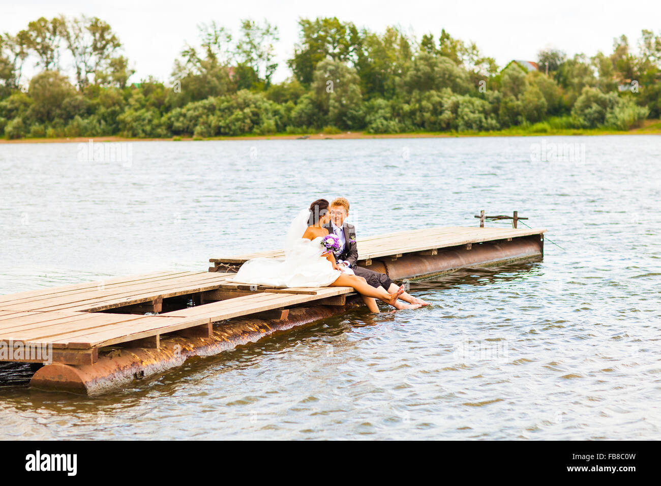 Beautiful bride with groom by a lake. Kiss and hug each other Stock ...