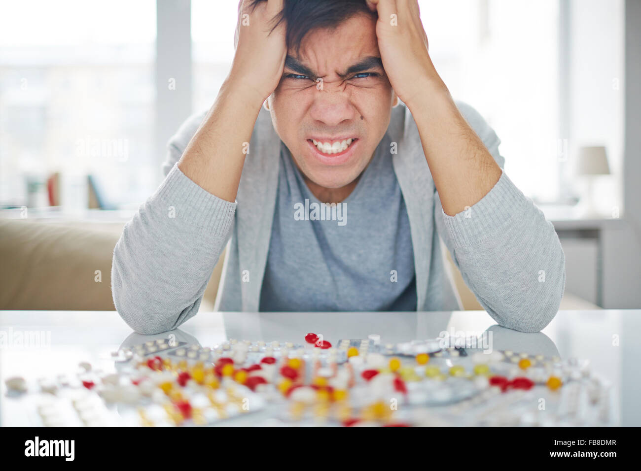 Angry man sitting at the table with pills on it Stock Photo - Alamy