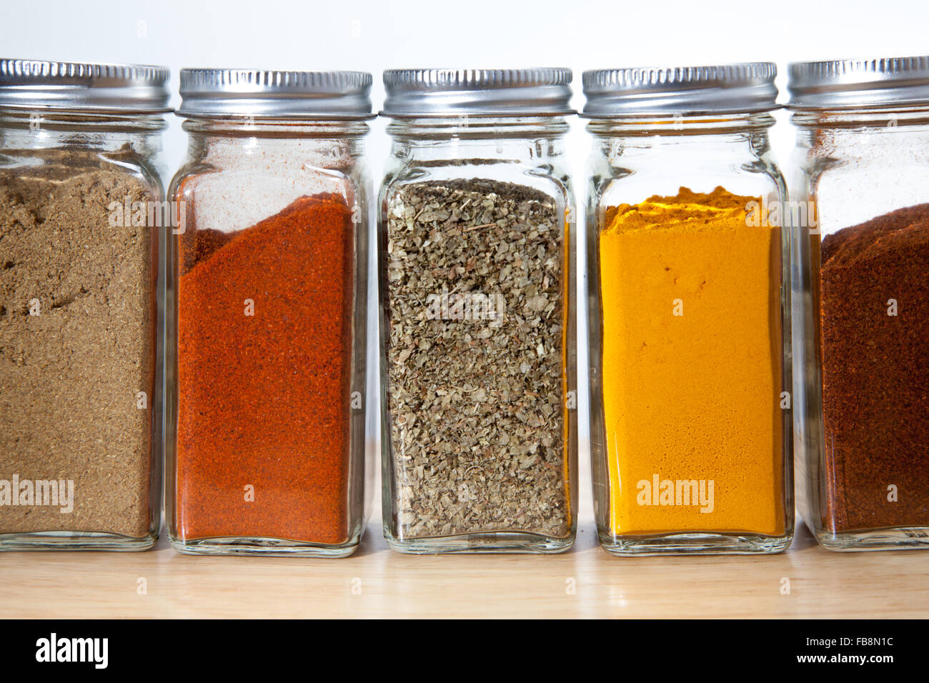 Spices in simple square jars on a wood table with white backgroud Stock ...