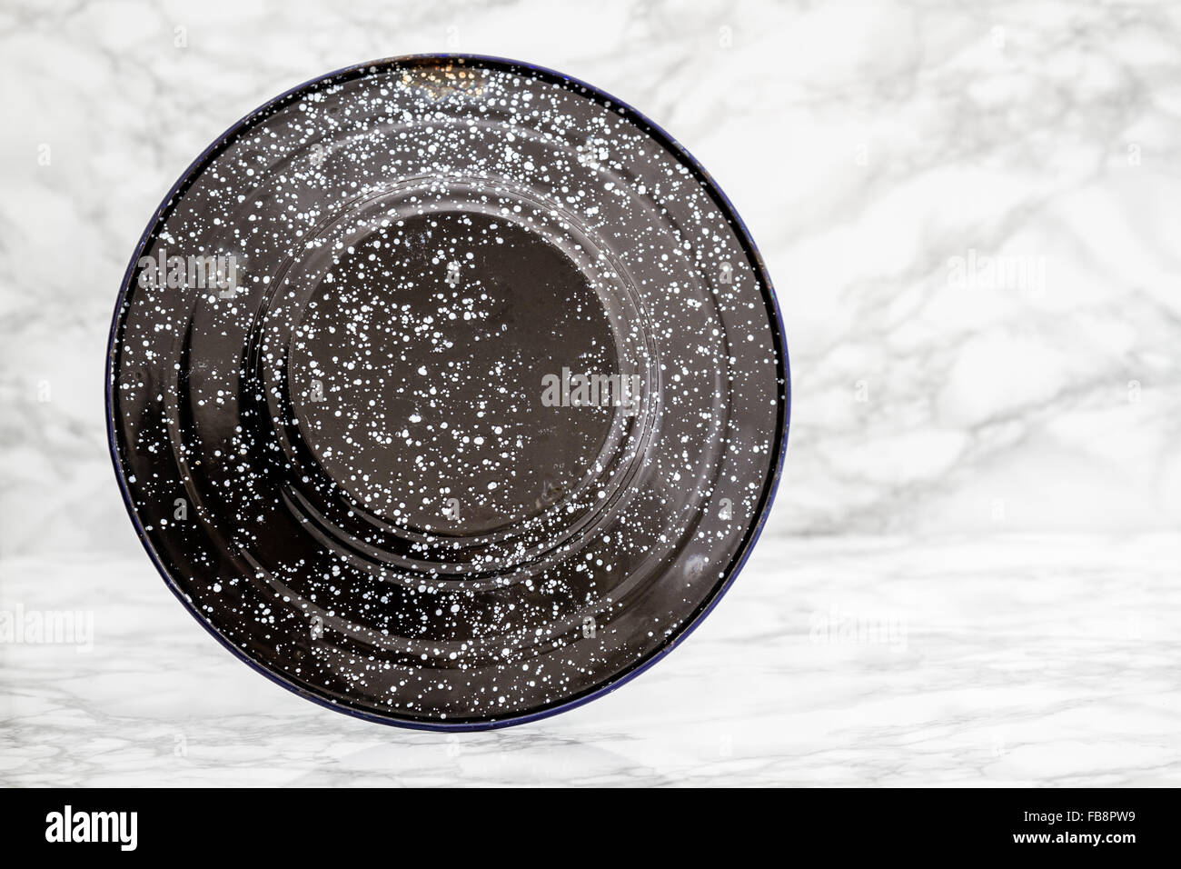 Backside of an empty vintage enamel plate on white marble background ...