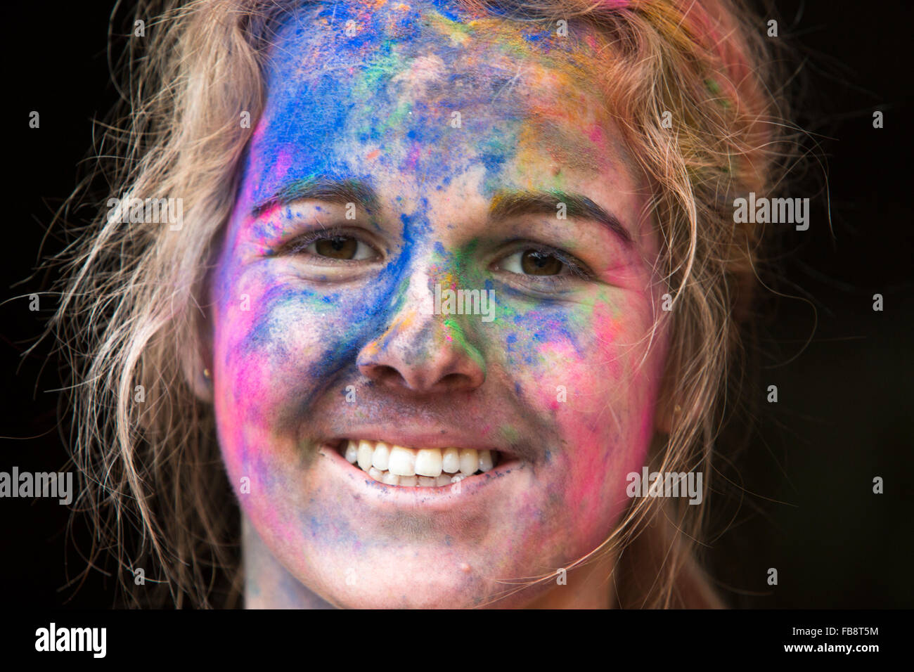 Pretty teenage girl with her face splattered with colourful paint after ...
