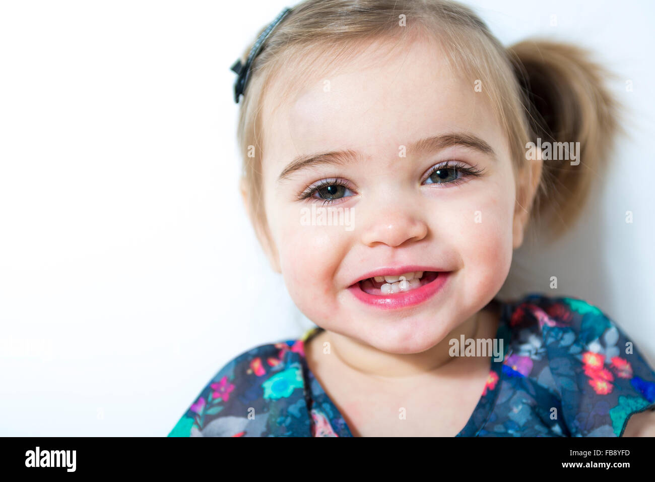 Smiling little baby girl sitting close to a wall Stock Photo - Alamy
