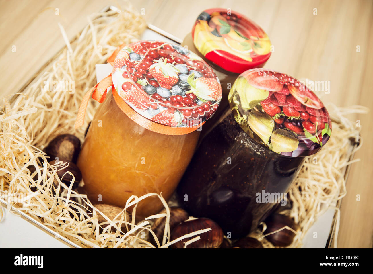 Tasty jam in the glass jars with chestnuts in hay. Seasonal food theme ...