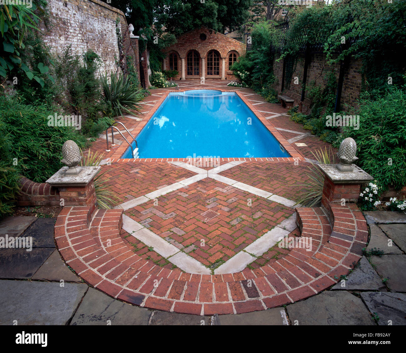 Brick paving around turquoise rectangular swimming pool in large ...