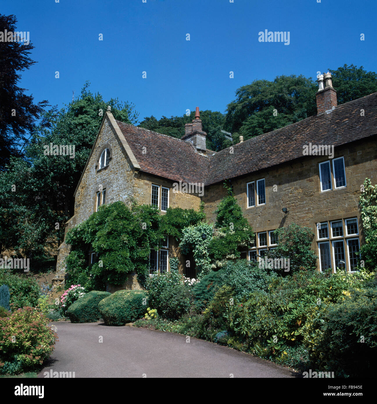 Exterior of stone country house with green shrubs in border Stock Photo ...