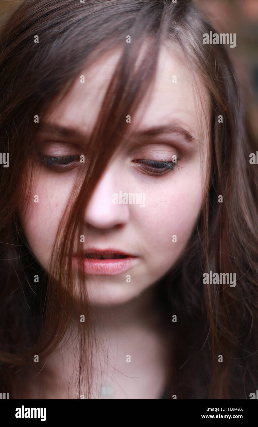 Portrait of a young woman with eyes cast down and hair falling on her ...