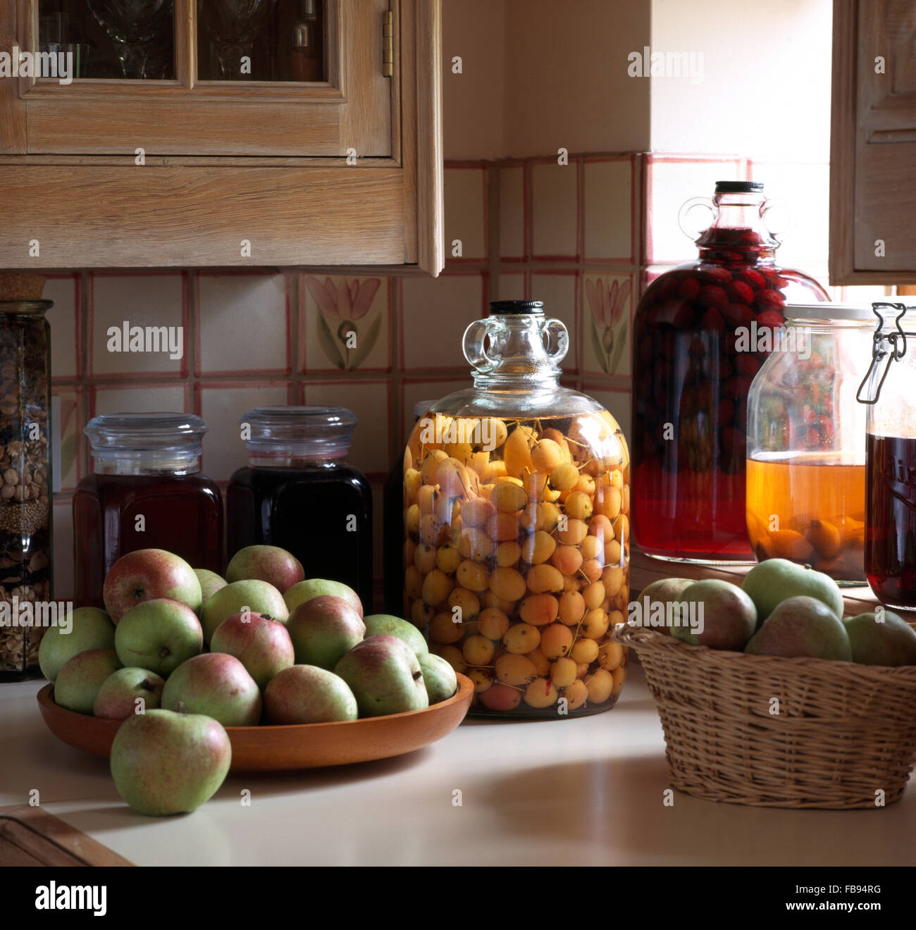 Close-up of baskets of apples on kitchen worktop with jars of jam and ...