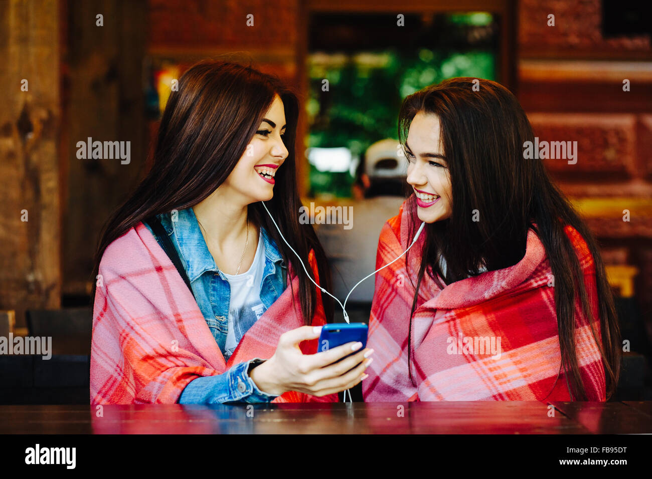 Two girl sitting listening music Stock Photo - Alamy