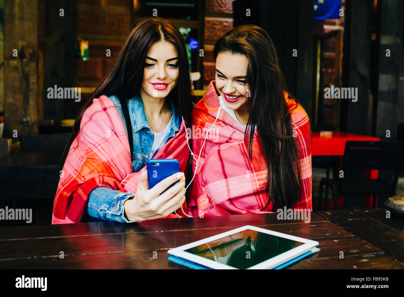 Two girl sitting listening music Stock Photo - Alamy