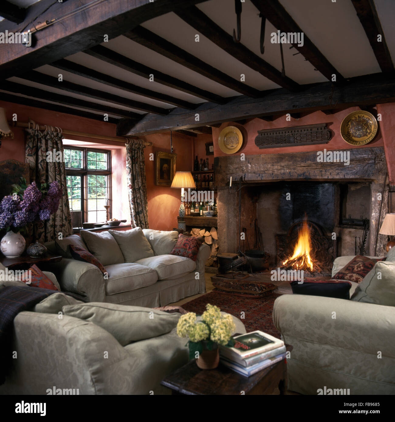 White damask sofas around fireplace with lighted fire in a nineties ...