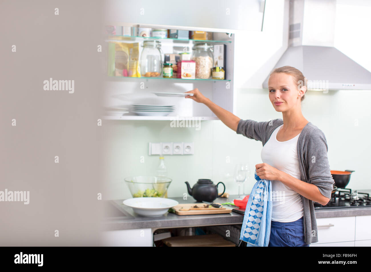 Young woman washing dishes in her modern kitchen, using a dishwasher ...