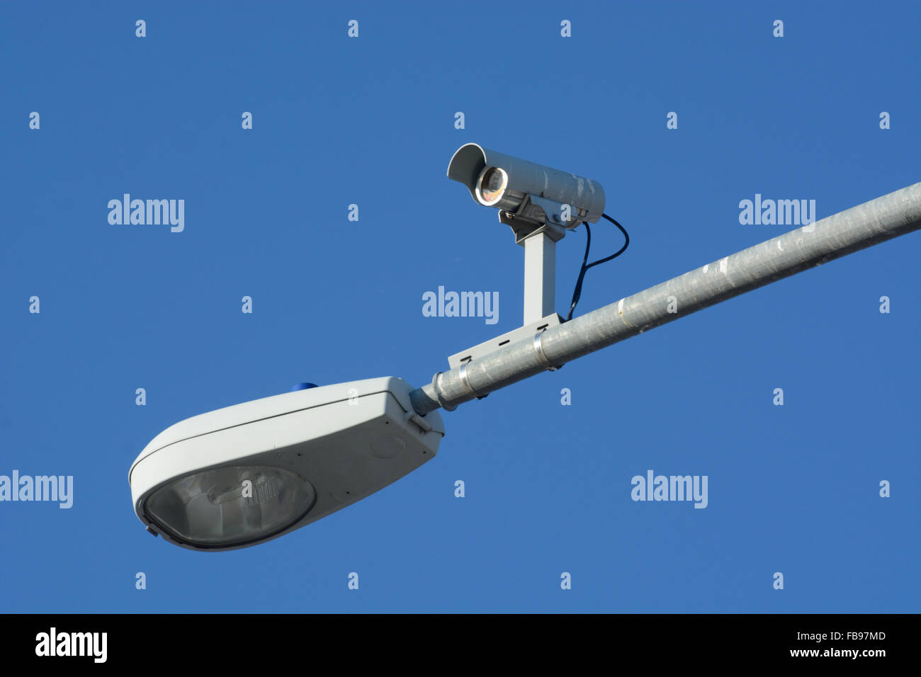 Urban street lamp with traffic surveillance camera against blue sky ...