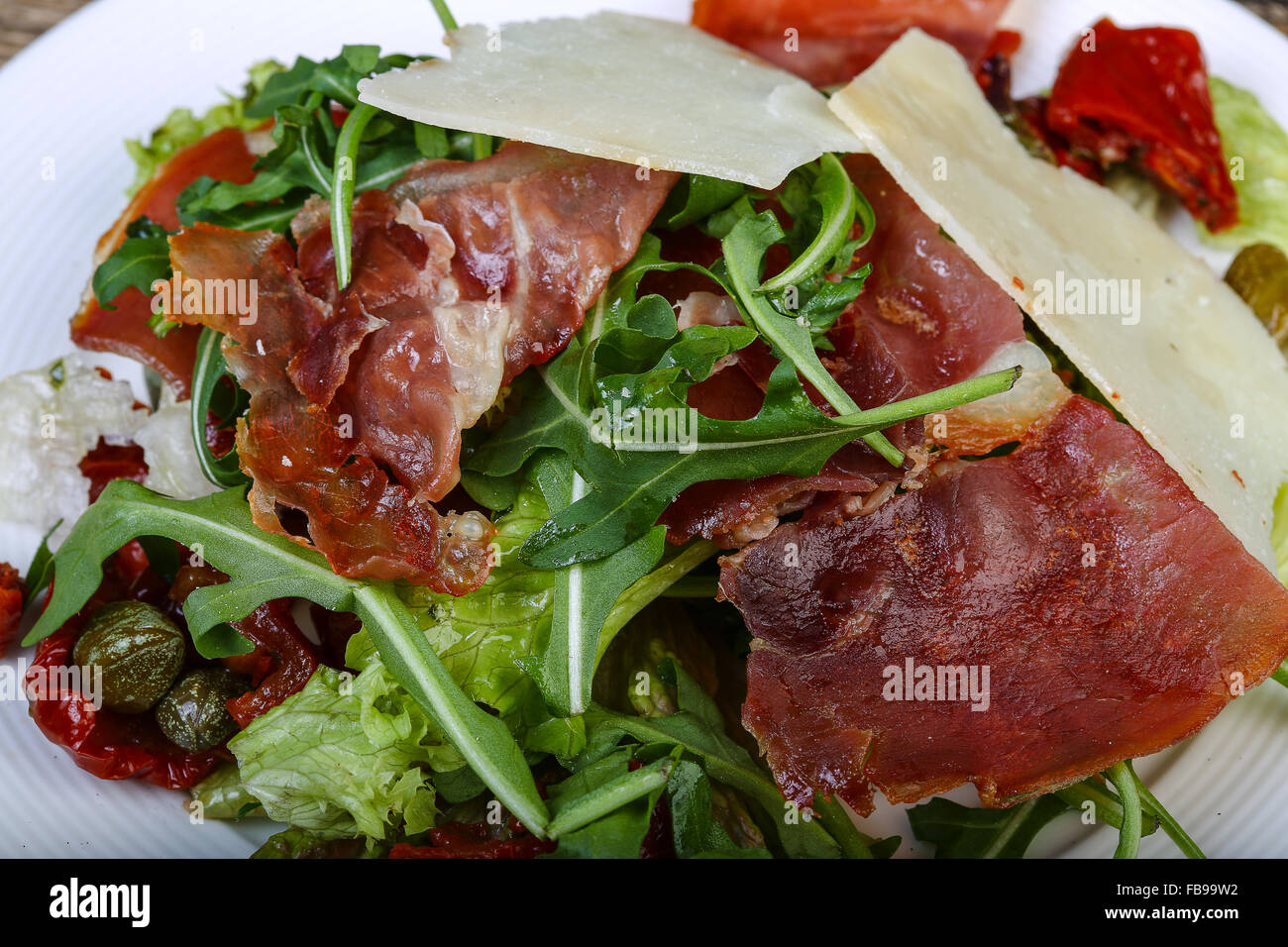 Salad with prosciutto, parmesan, dry tomato and ruccola Stock Photo - Alamy