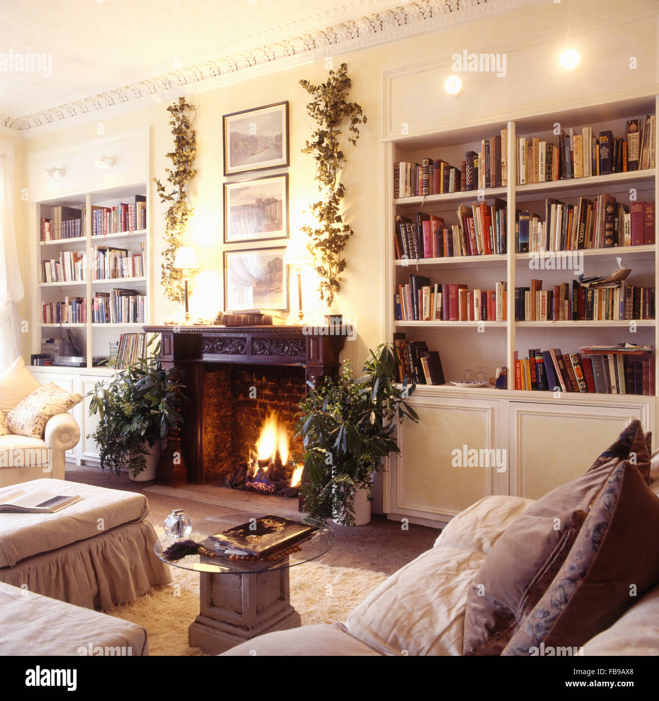 Jugs of foliage either side of fireplace with lighted fire in eighties ...