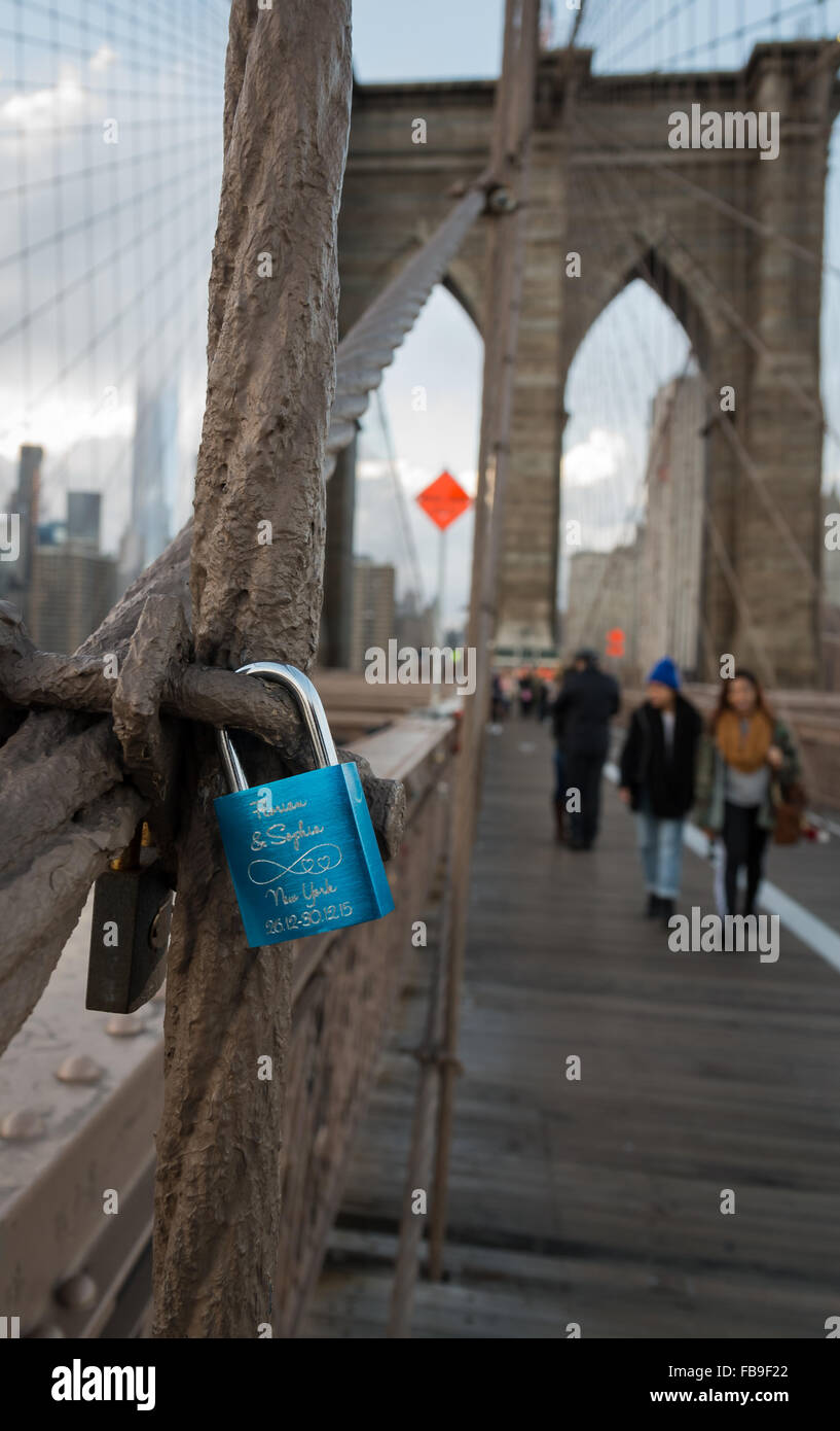 An engraved love lock padlock on Brooklyn Bridge with people walking ...