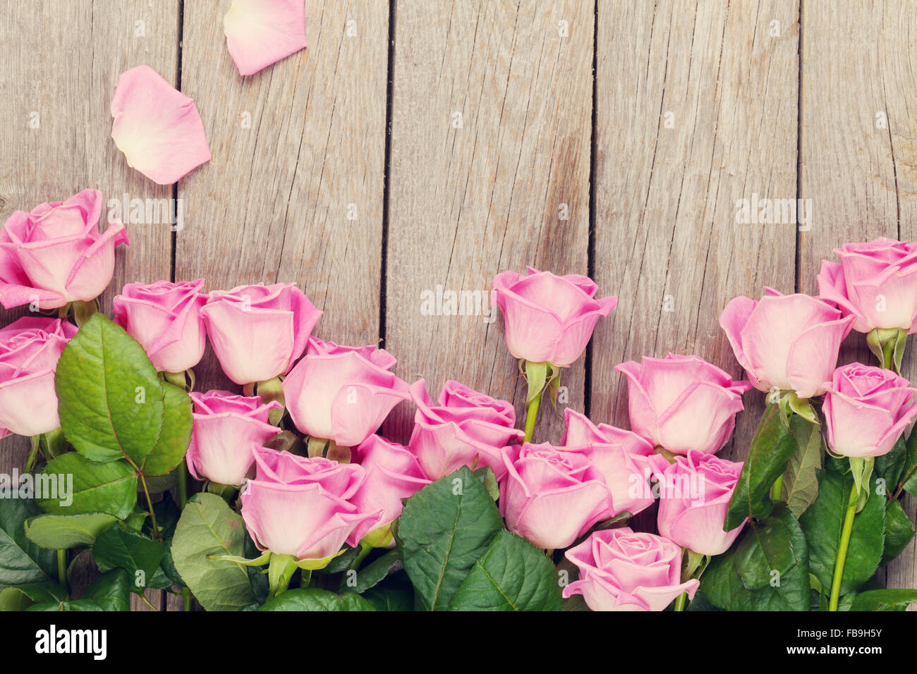 Pink roses bouquet over wooden table. Top view with copy space. Toned ...