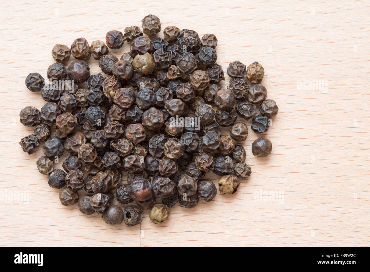 Black pepper corns on a wooden board Stock Photo - Alamy