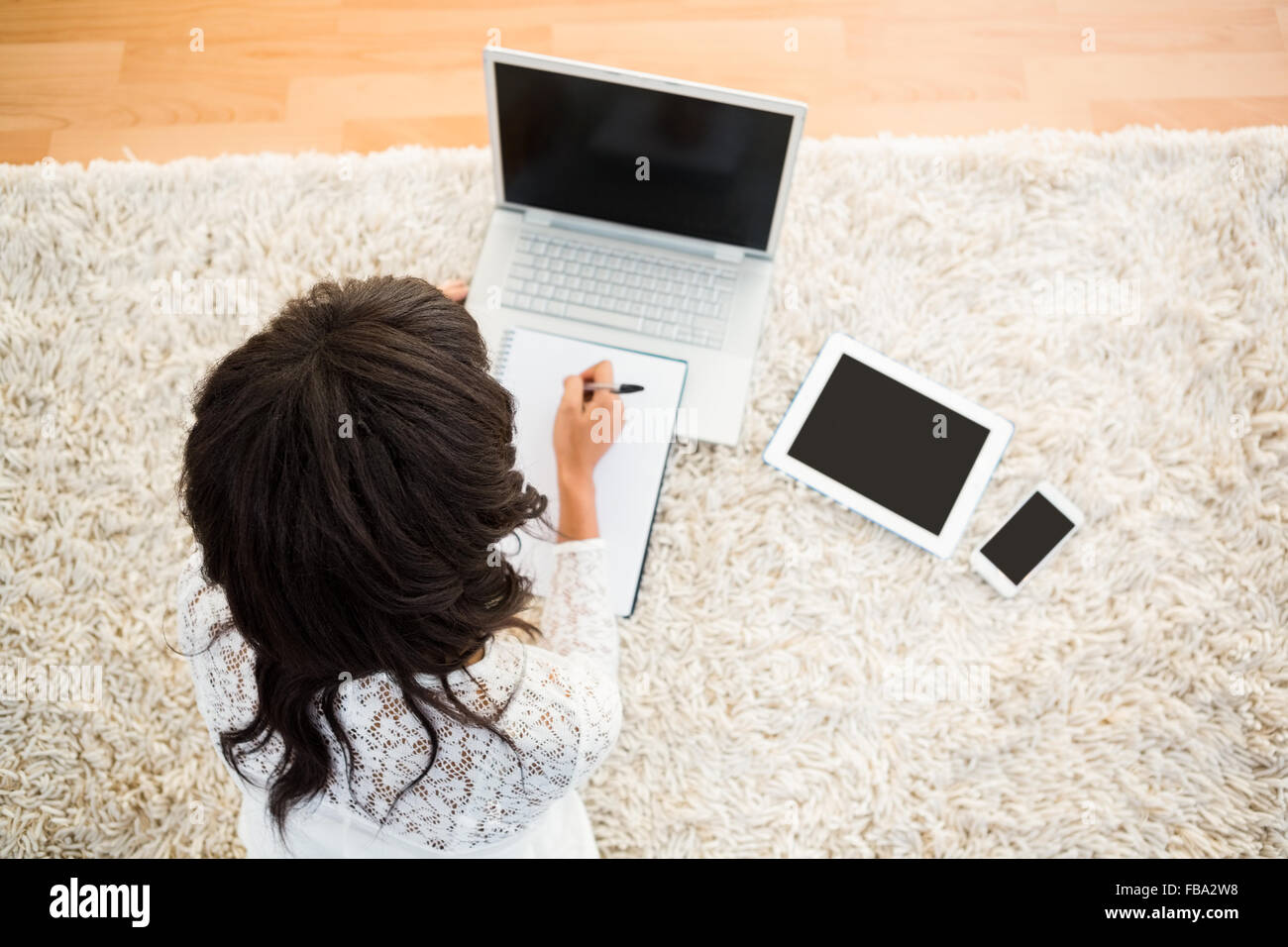 Above view of a woman writing note while using her laptop Stock Photo ...