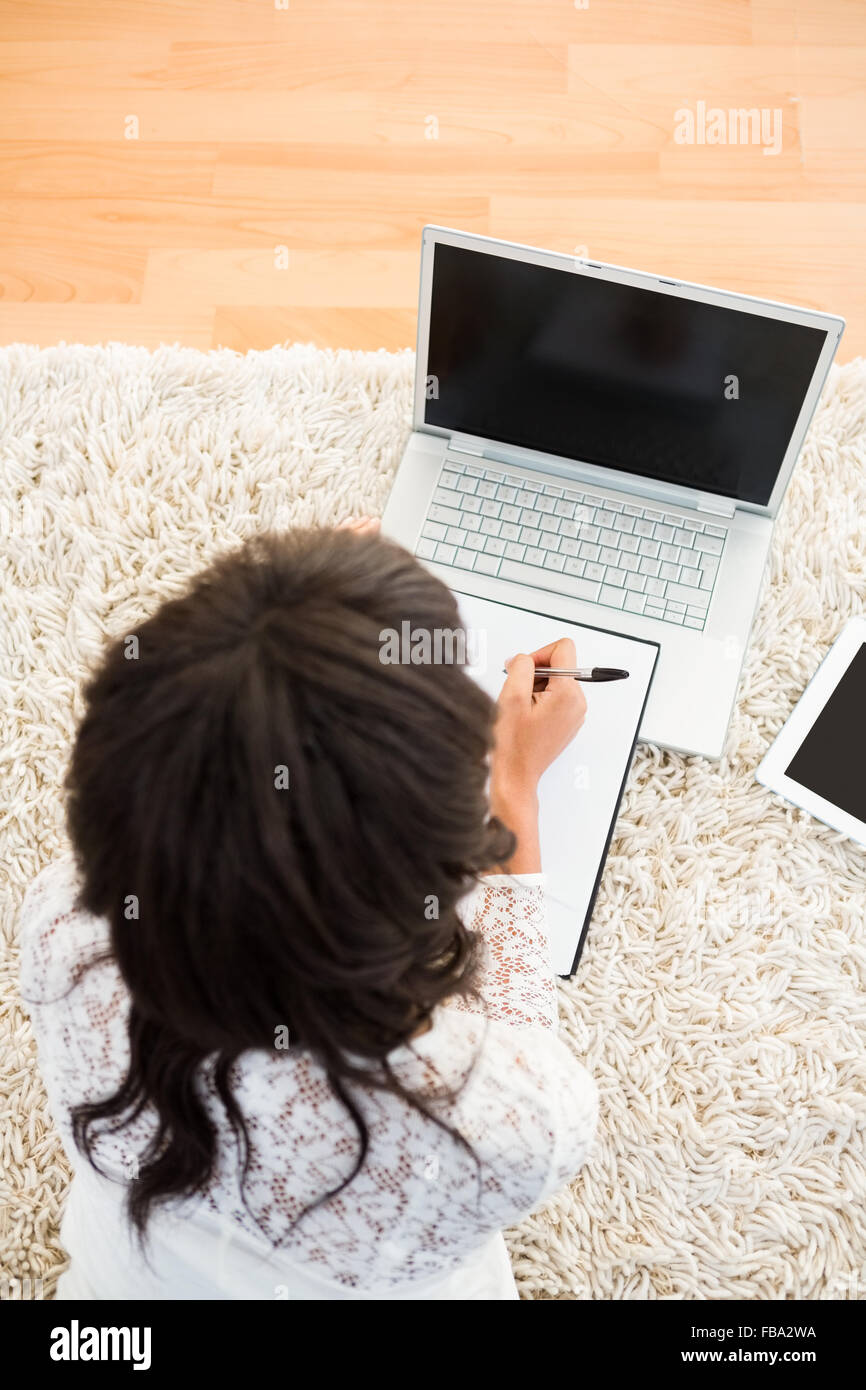 Above view of a woman writing note while using her laptop Stock Photo ...