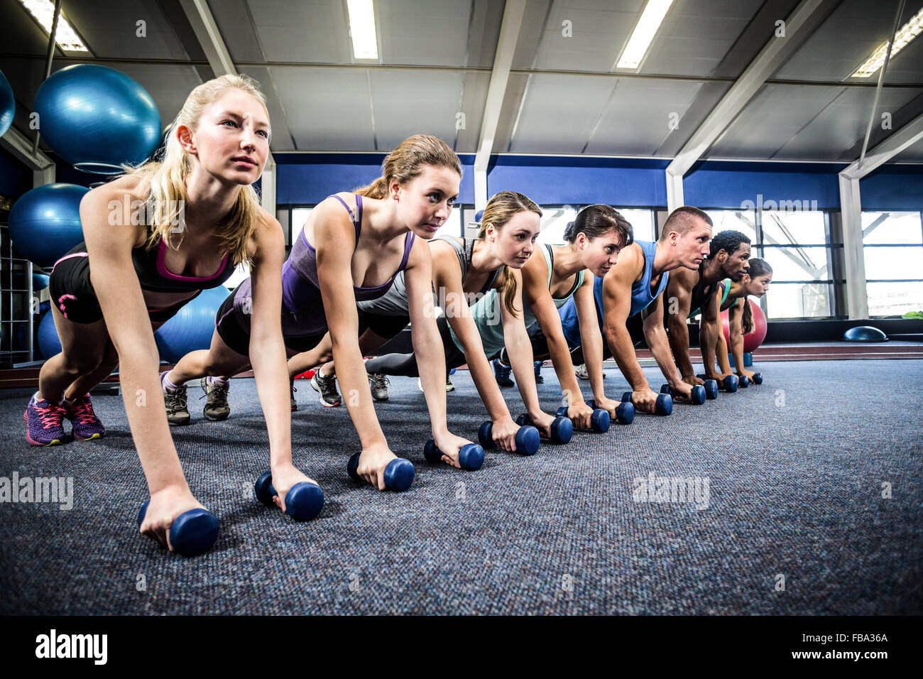Fitness class in plank position with dumbbells Stock Photo - Alamy