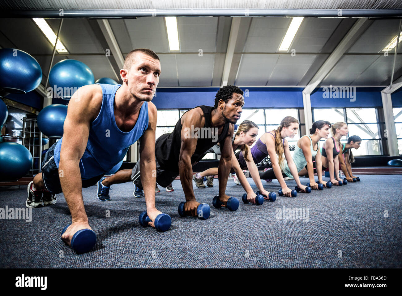 Fitness class in plank position with dumbbells Stock Photo - Alamy