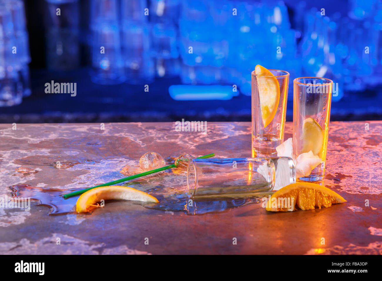 The spilled cocktails with ice cubes on blue color in the bar. concept ...