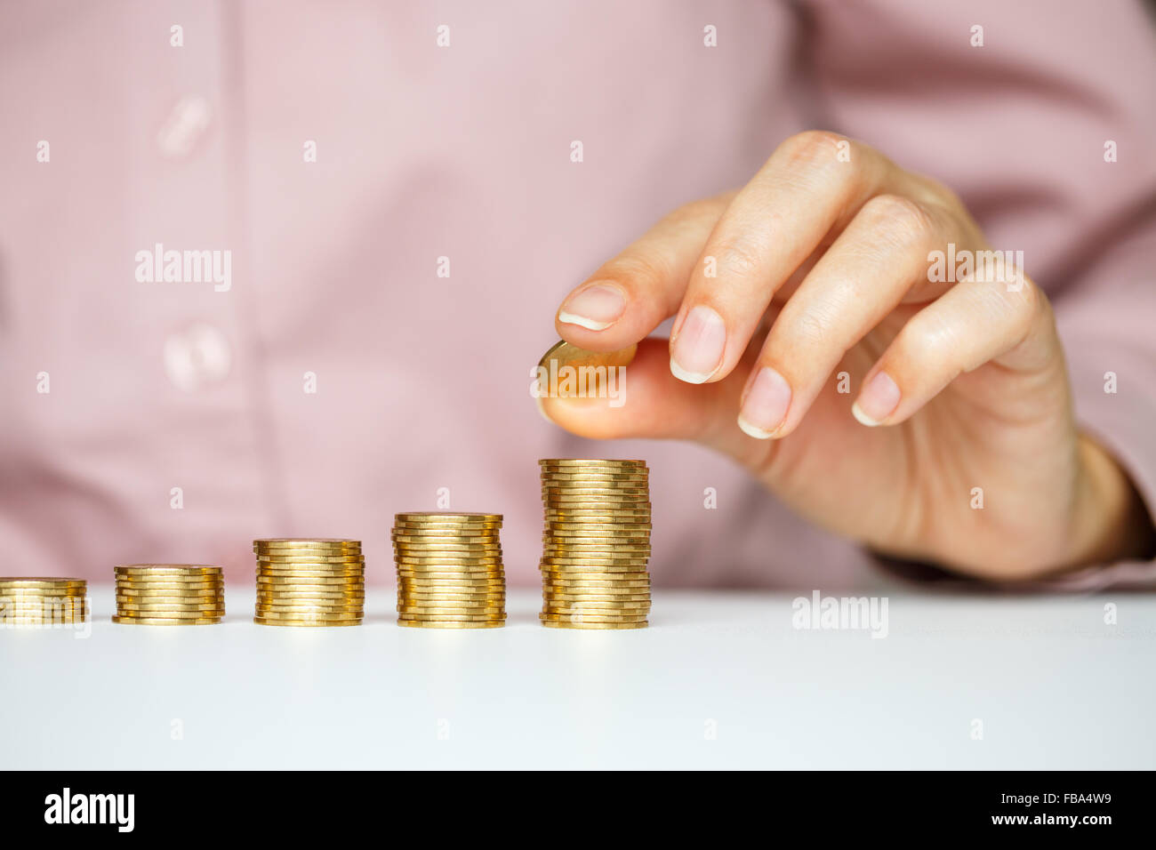 Savings, female hand stacking gold coins into increasing columns Stock ...