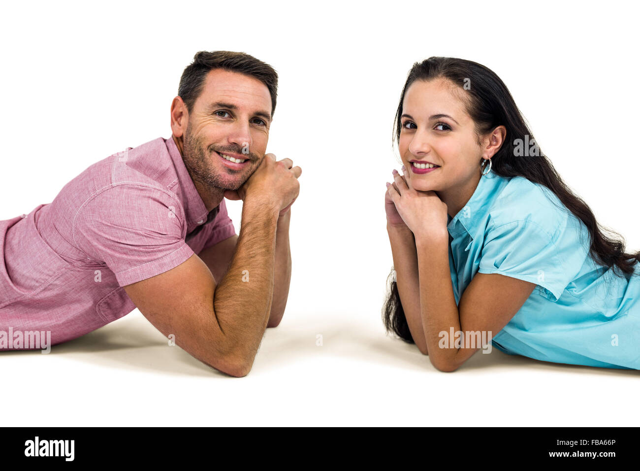 Smiling couple laying on the floor face to face looking at the camera ...