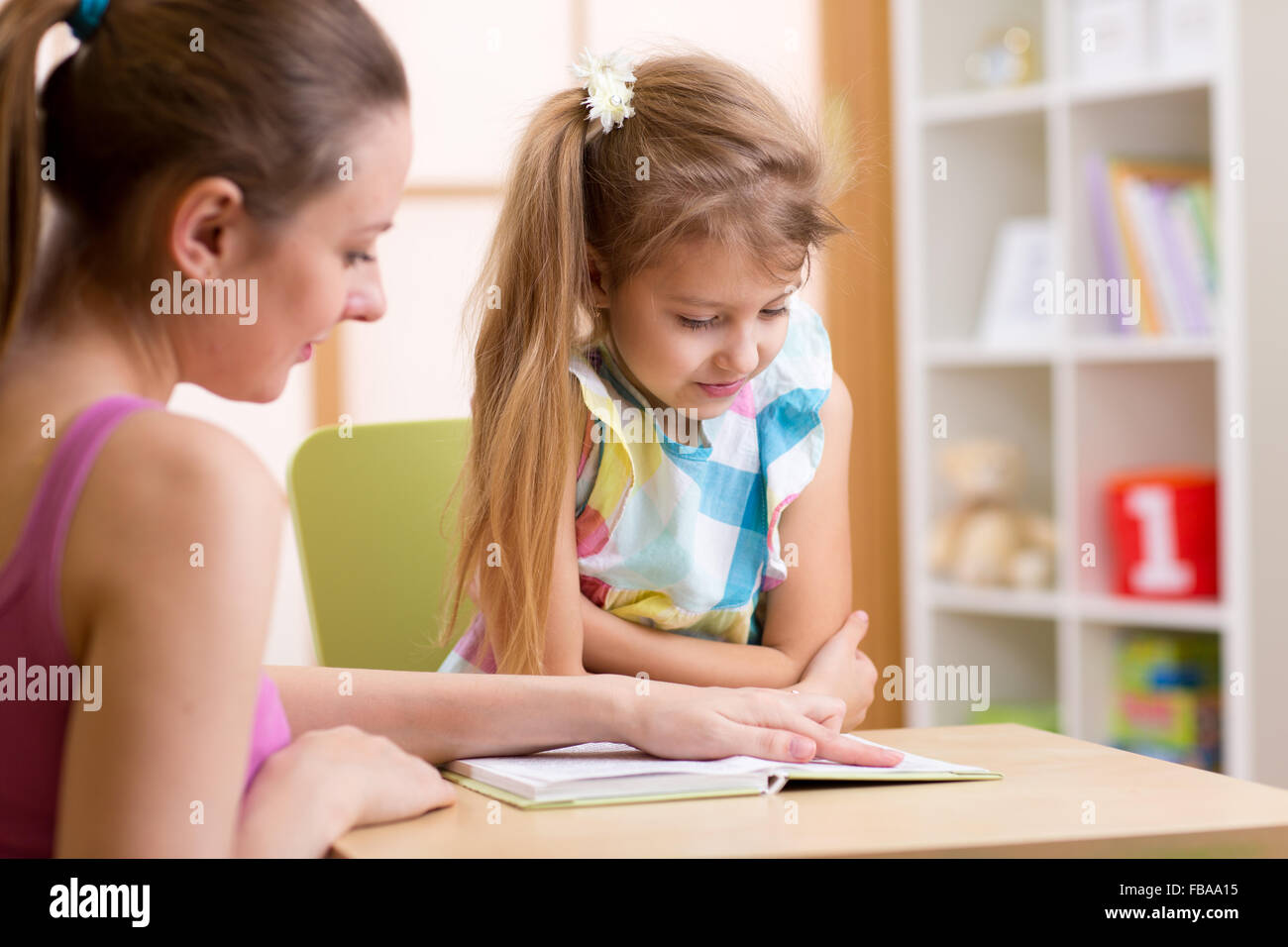 Elementary Pupil Reading With Teacher Stock Photo - Alamy