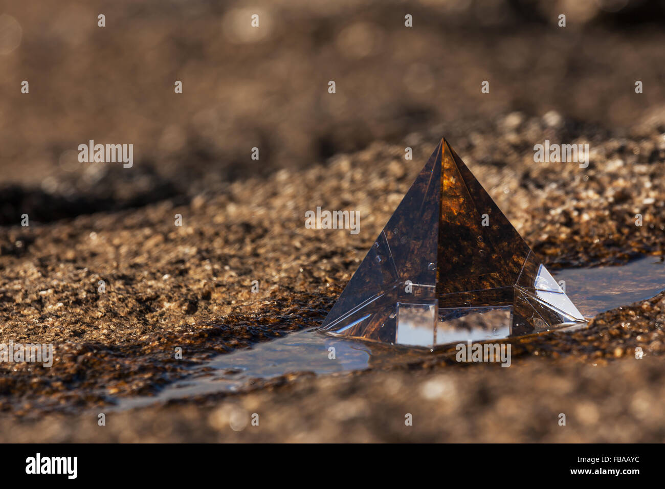 A glass pyramid in a puddle on rocks Stock Photo - Alamy