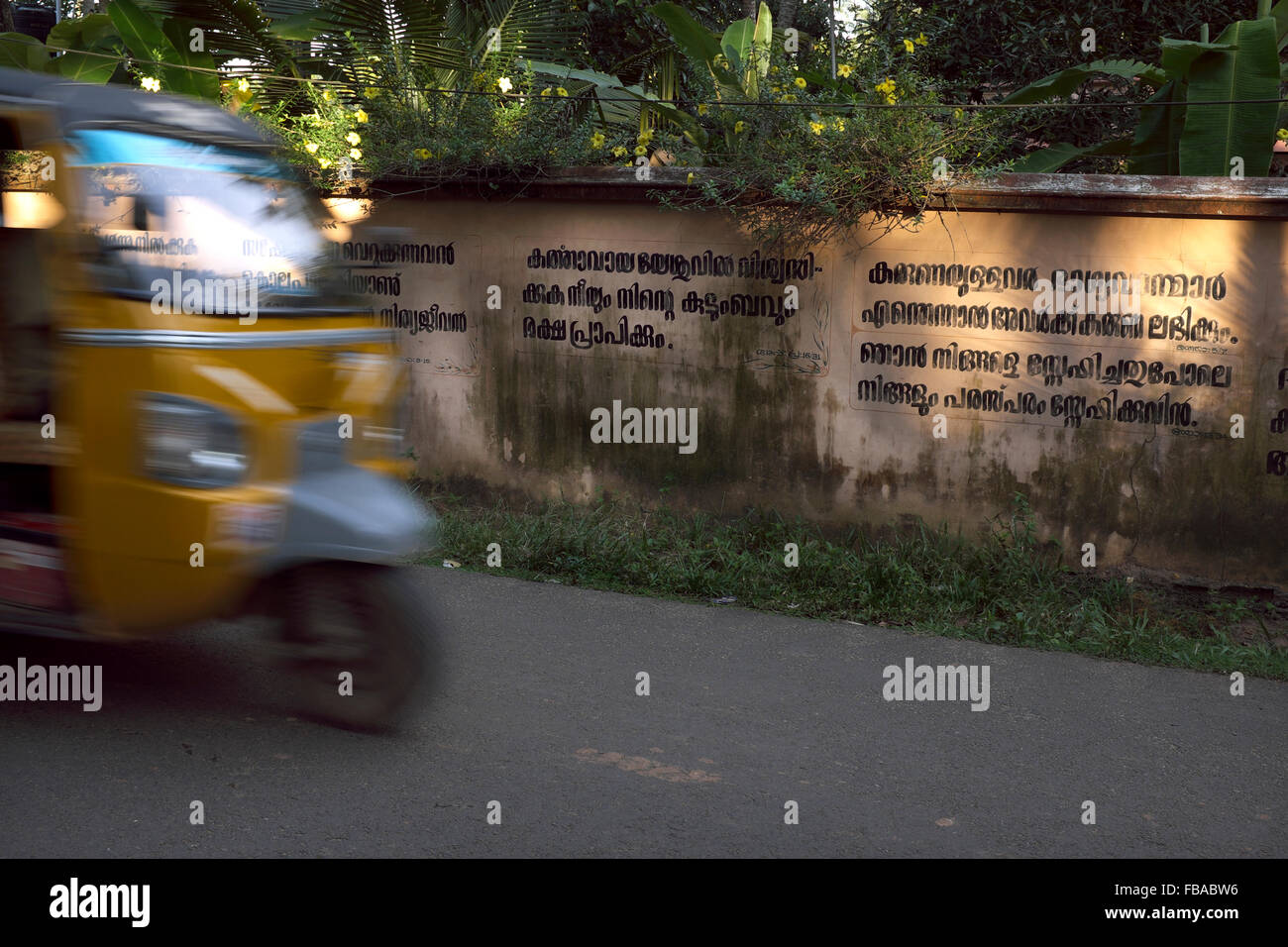 An auto-rickshaw passes a sign on a wall in Allepuzha (Alleppey ...