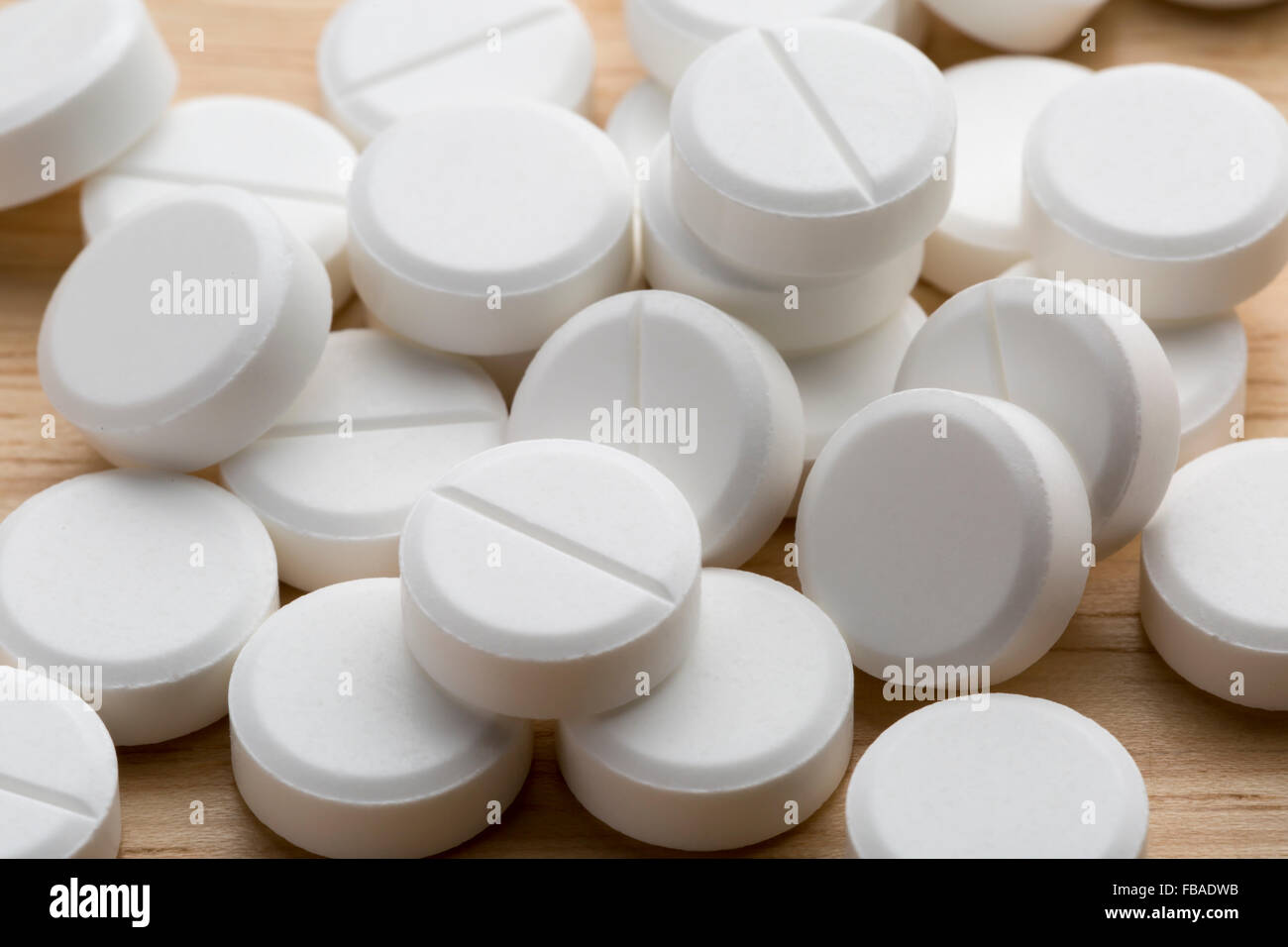 Heap of white round tablets on a wooden background Stock Photo - Alamy
