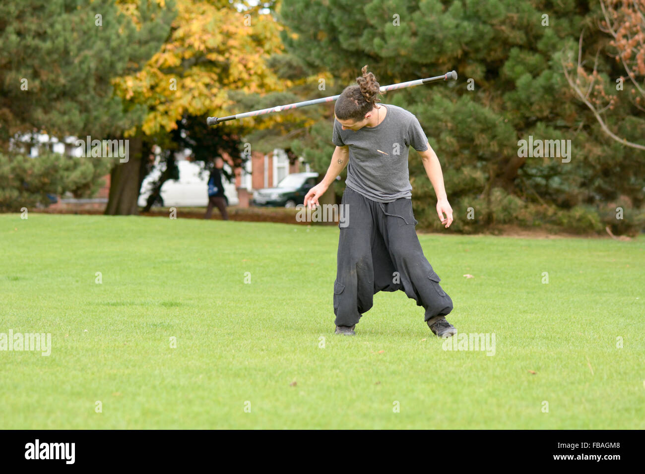Fire Performer practicing moves with pole in daytime in park in Bedford ...