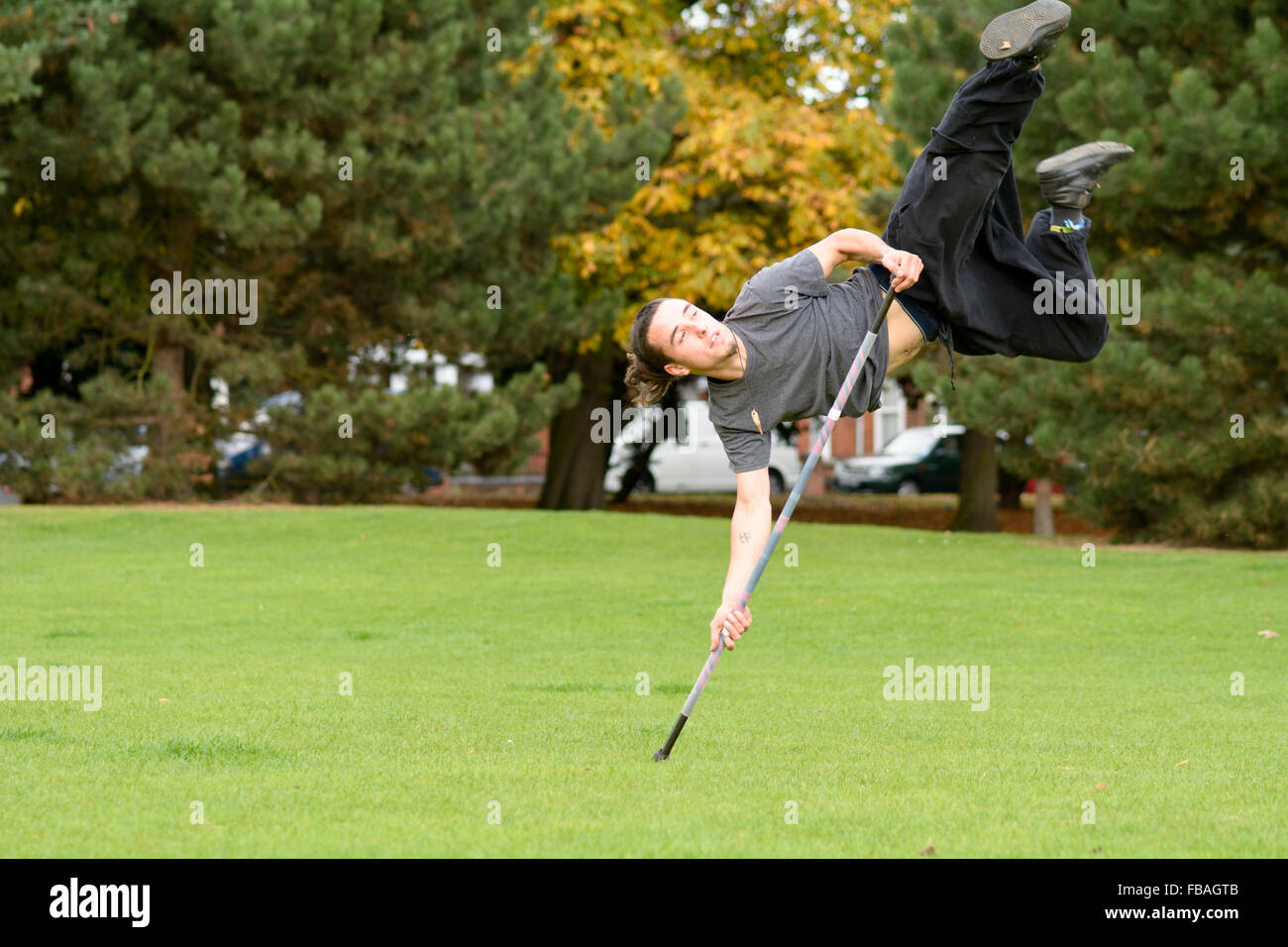 Fire Performer practicing moves with pole in daytime in park in Bedford ...
