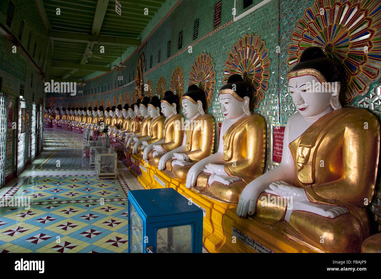 Long row of painted stone Buddhas against a green temple wall in the ...