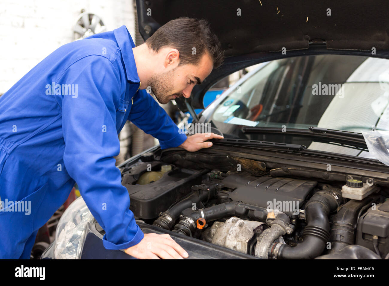 View of a Young attractive mechanic working on a car at the garage ...