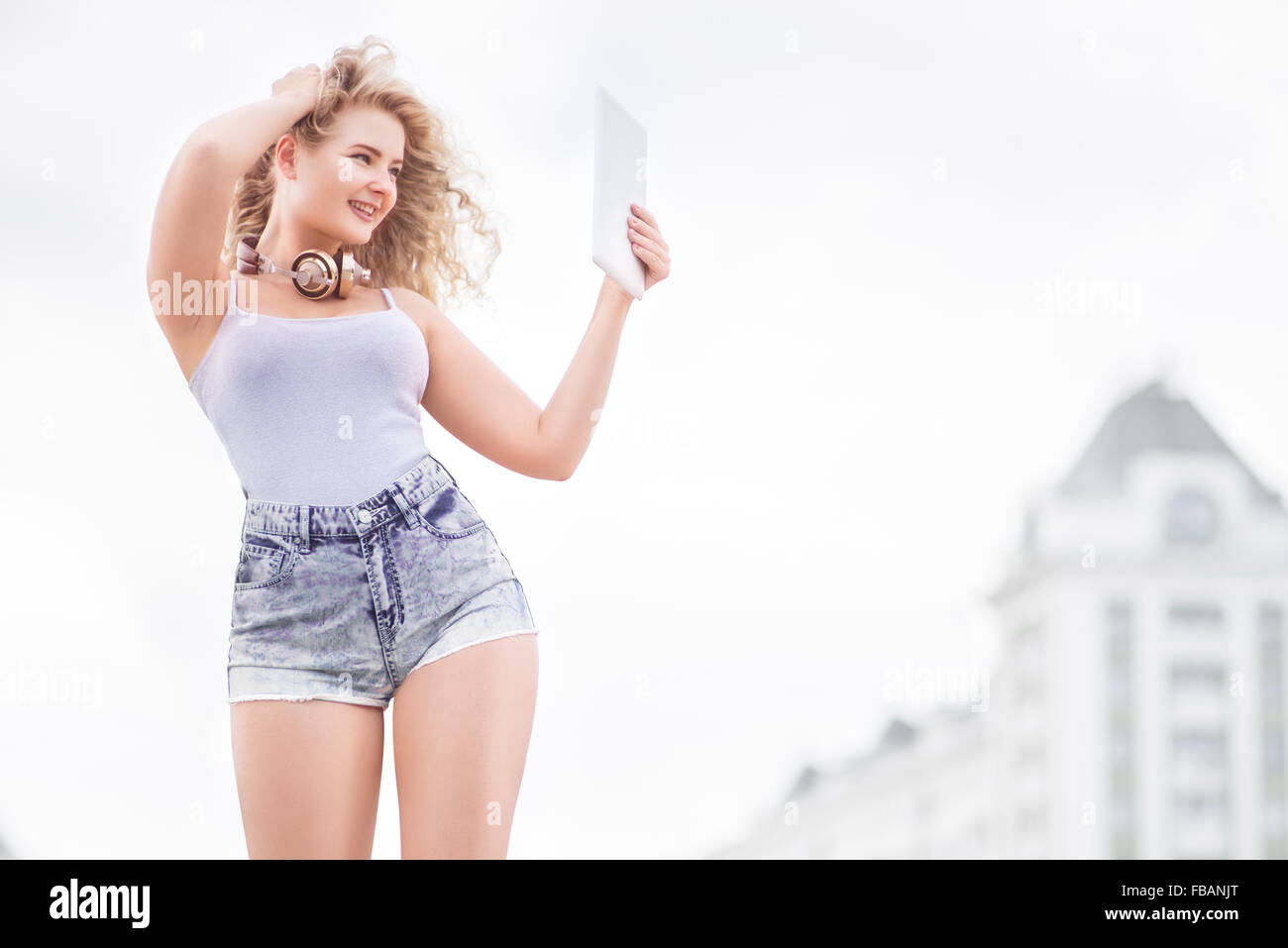 Happy young woman with vintage music headphones around her neck, taking ...