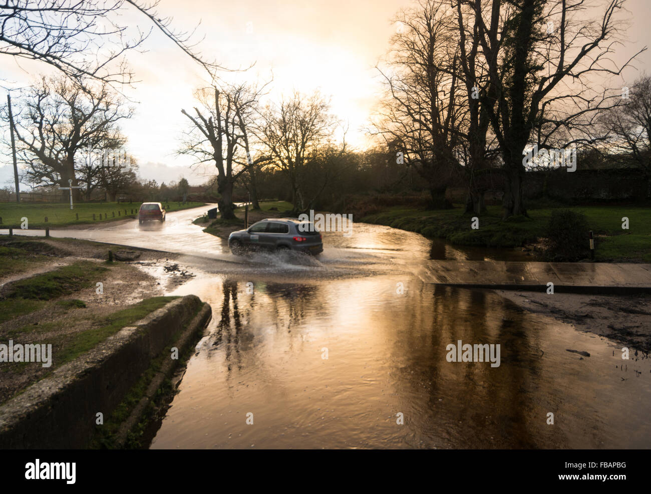 Car driving through a flooded ford in the New Forest near Ringwood ...
