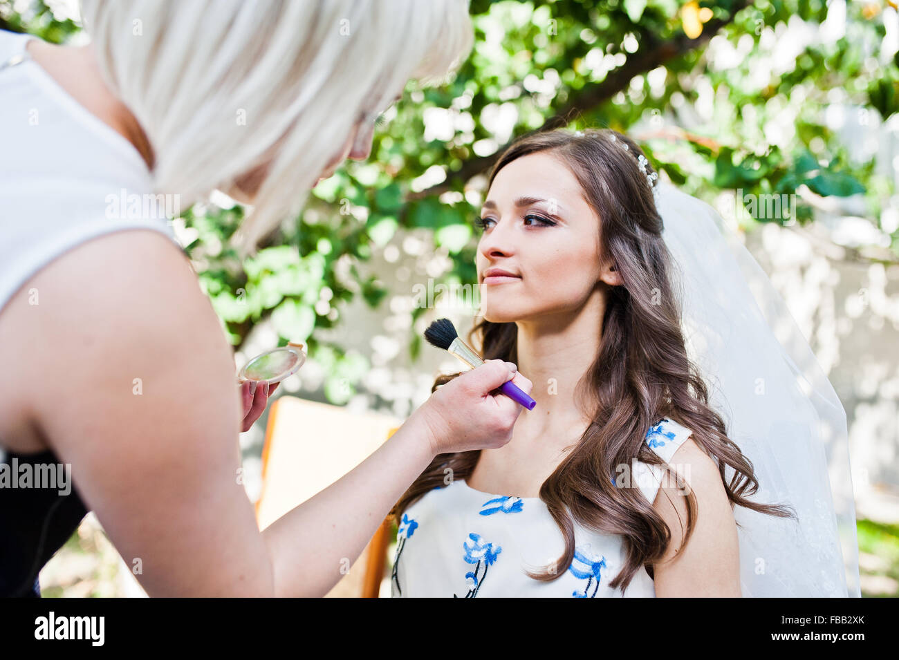 Master makeup artist doing makeup bride outdoors Stock Photo - Alamy