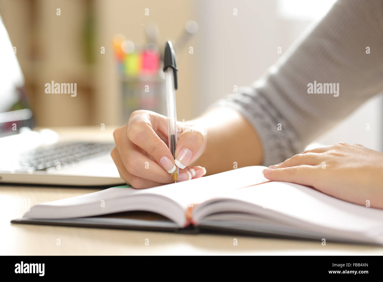 Close up of a woman hand writing in an agenda on a desk at home or ...