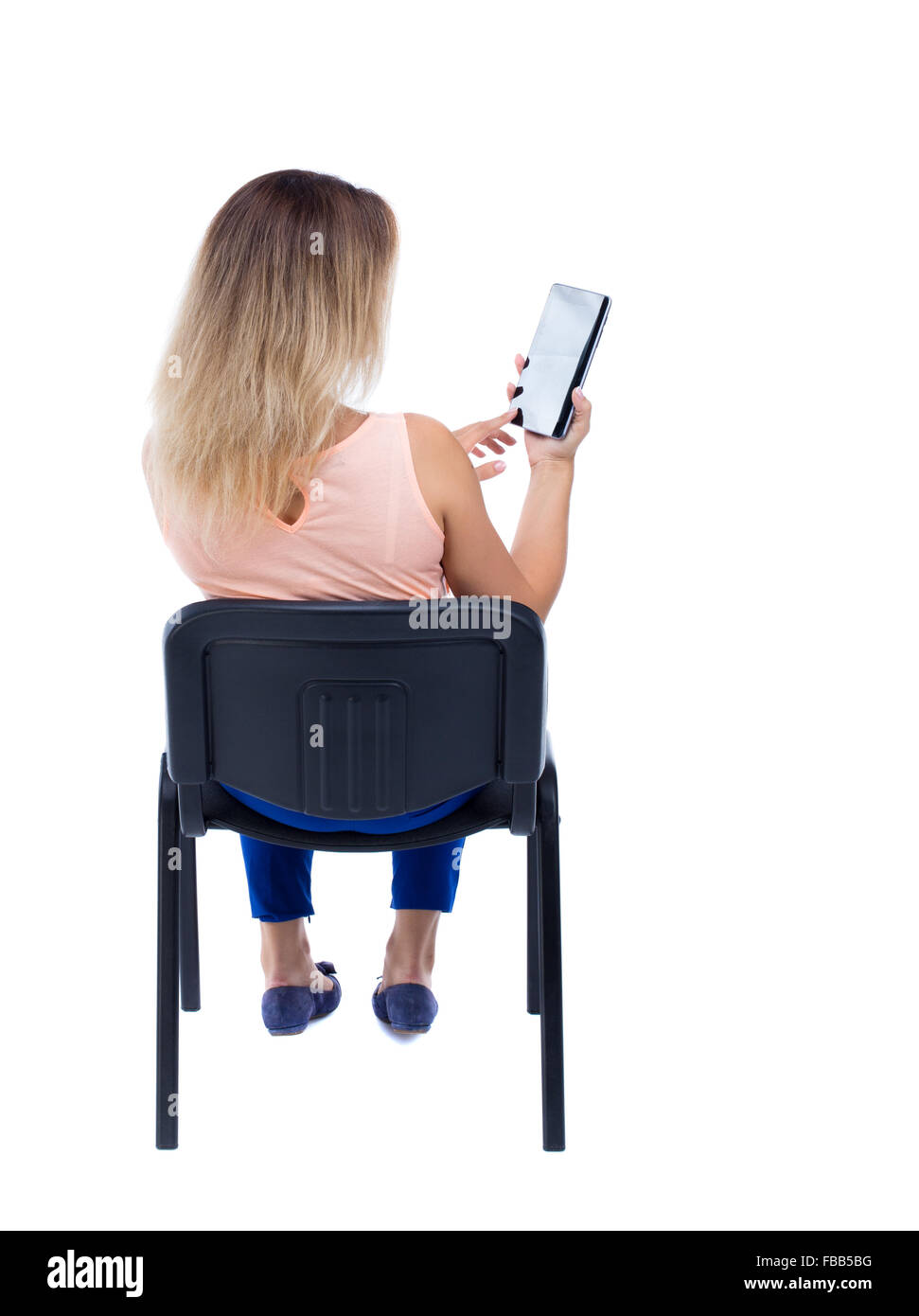 back view of woman sitting on chair and looks at the screen of the ...