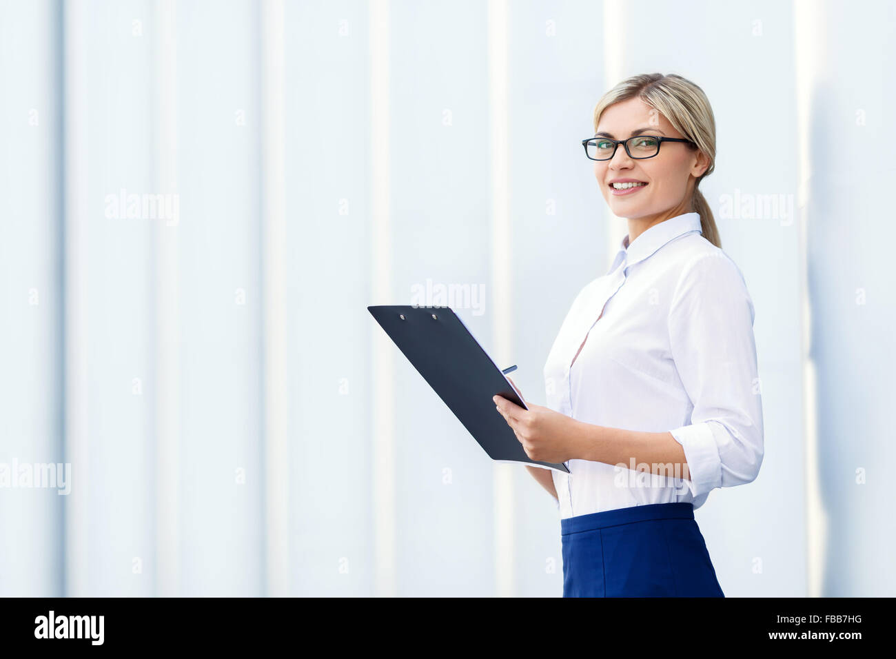 Cheerful business woman holding folder Stock Photo - Alamy