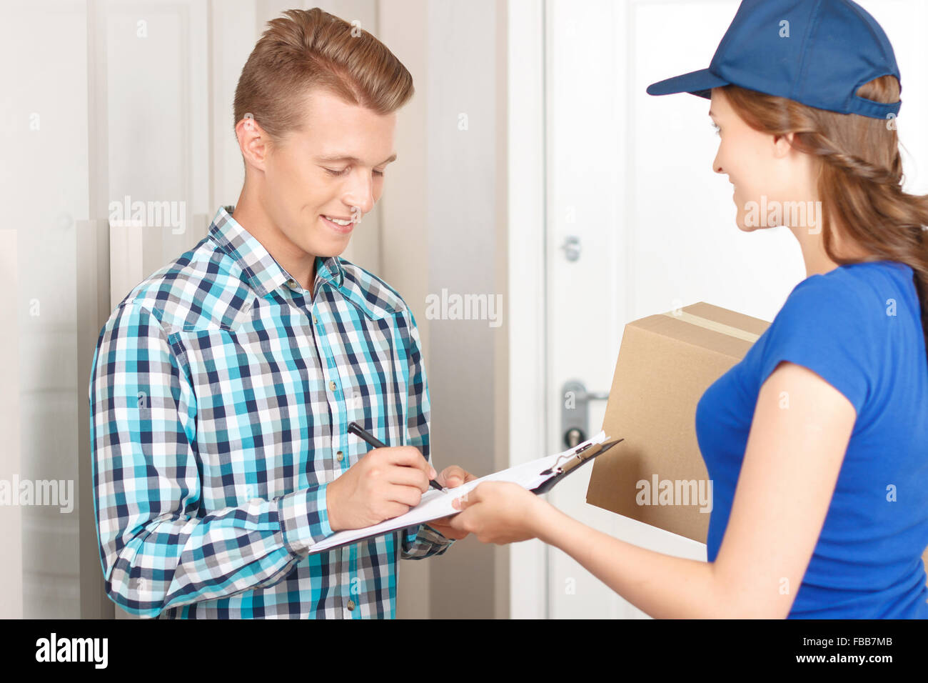 Positive deliverywoman delivering parcel Stock Photo - Alamy