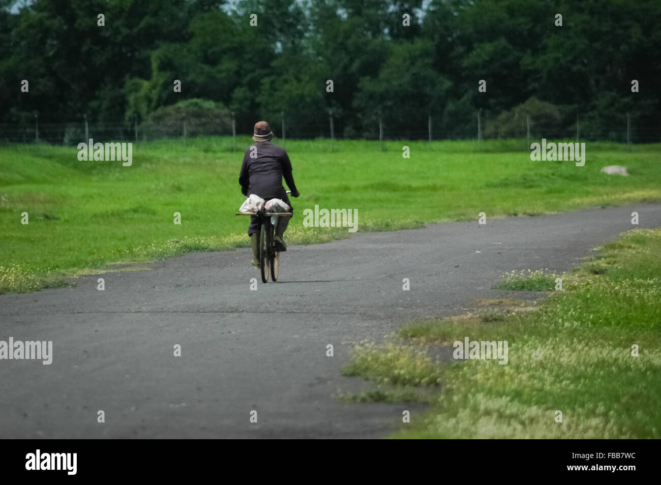 A man is riding his bicycle on a road in the buffer zone of Jakarta ...