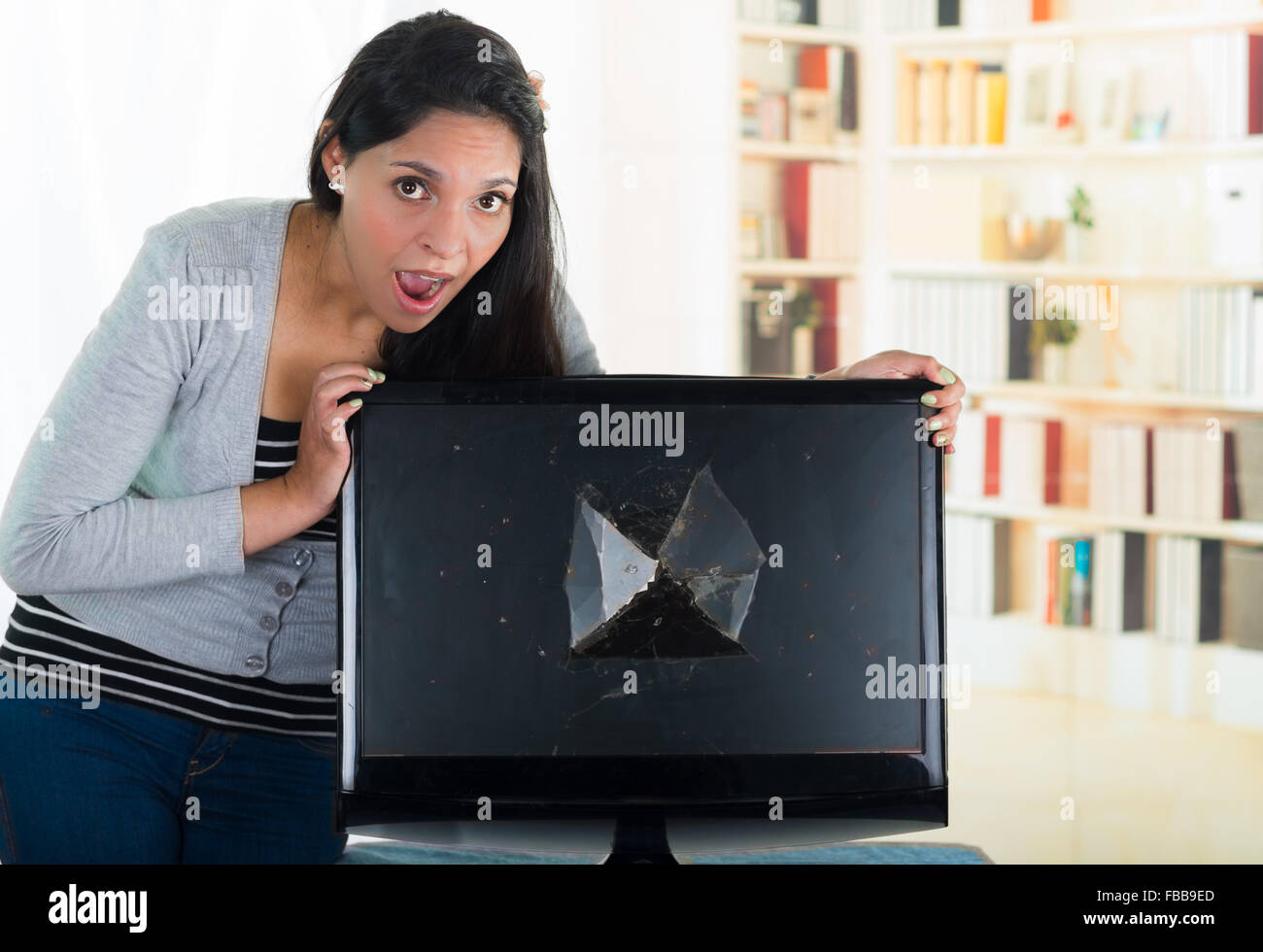 Brunette female looking over broken computer screen with shocked facial ...
