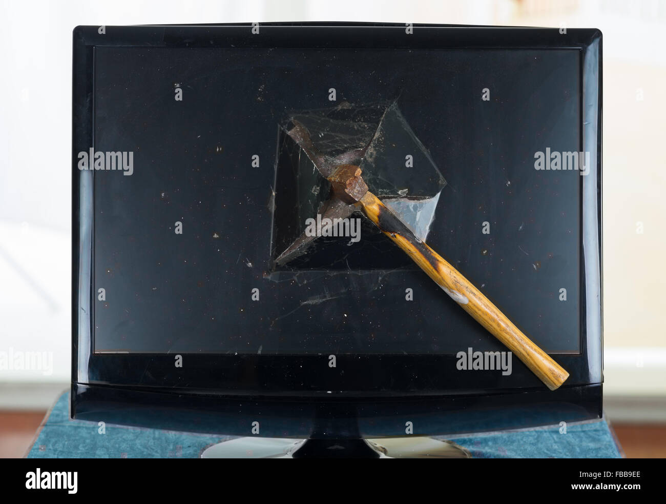 Standard hammer stuck inside broken computer screen Stock Photo - Alamy