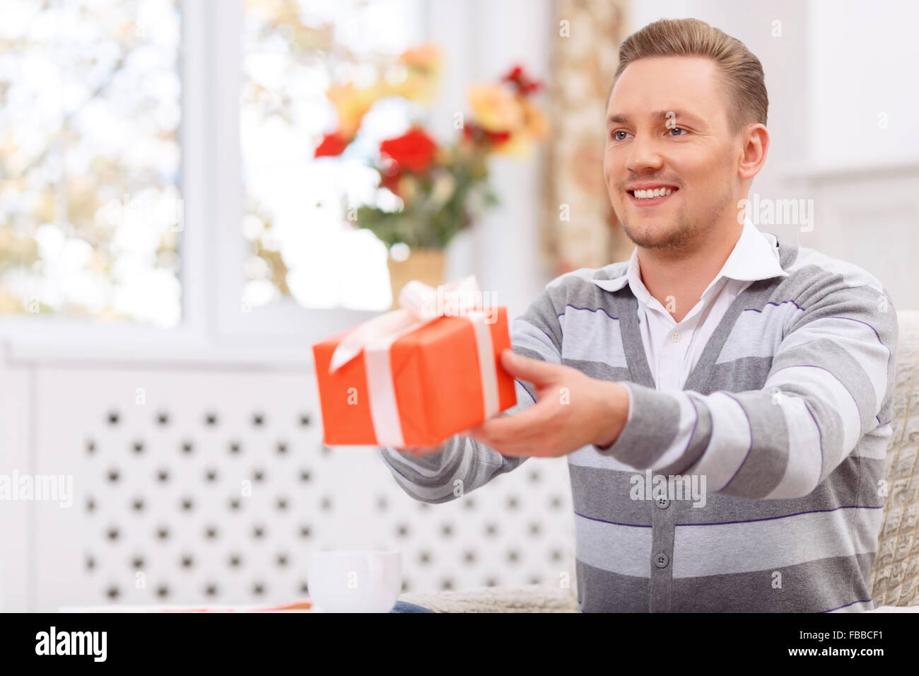 Pleasant man giving present Stock Photo - Alamy
