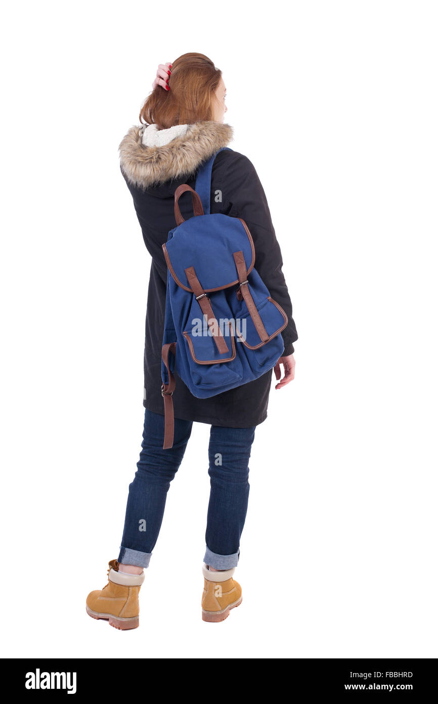 Back view woman in winter jacket with a backpack looking up. Standing ...