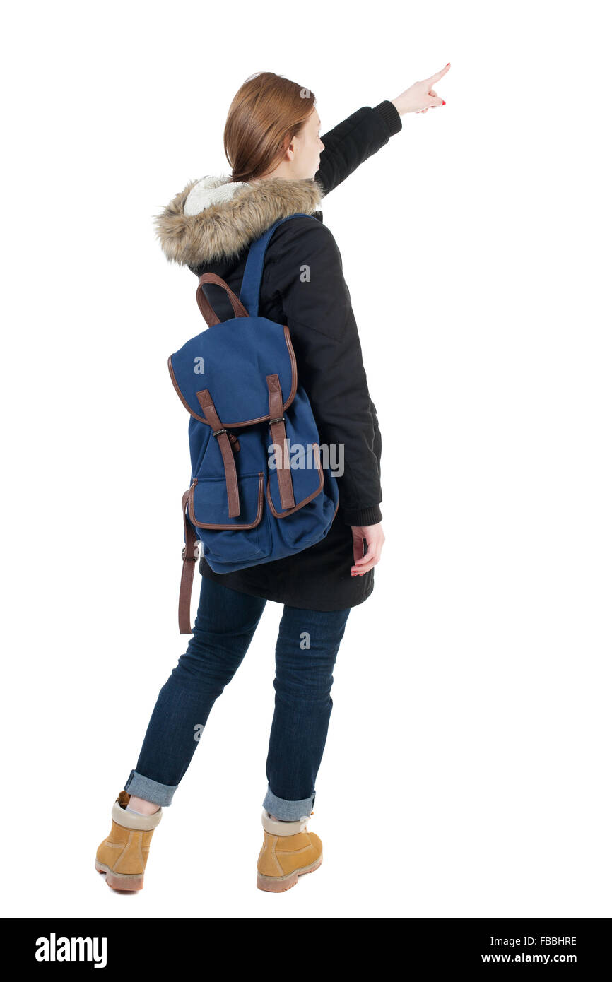 Back view of pointing young women in parka with backpack. Young girl ...