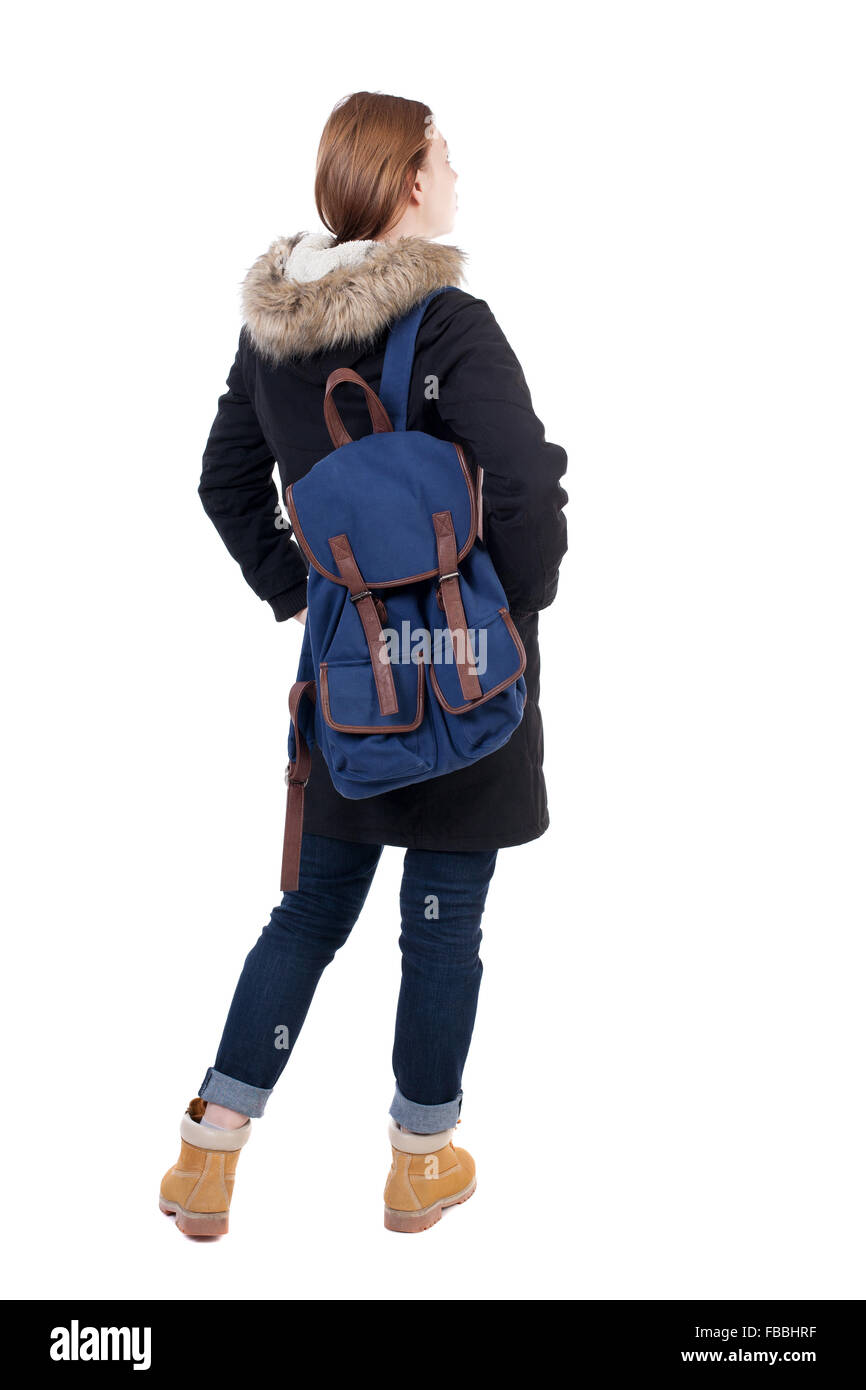 Back view woman in winter jacket with a backpack looking up. Standing ...